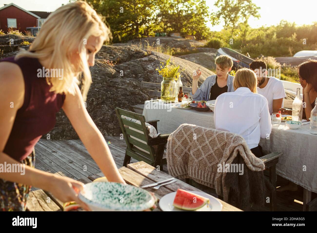 Woman picking watermelon slice while friends are enjoying food on ...