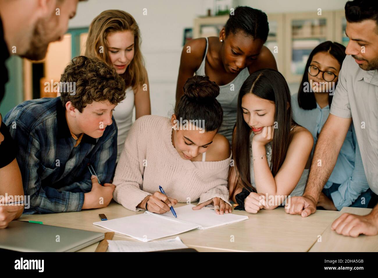 Female studying with friends while professor assisting in classroom ...