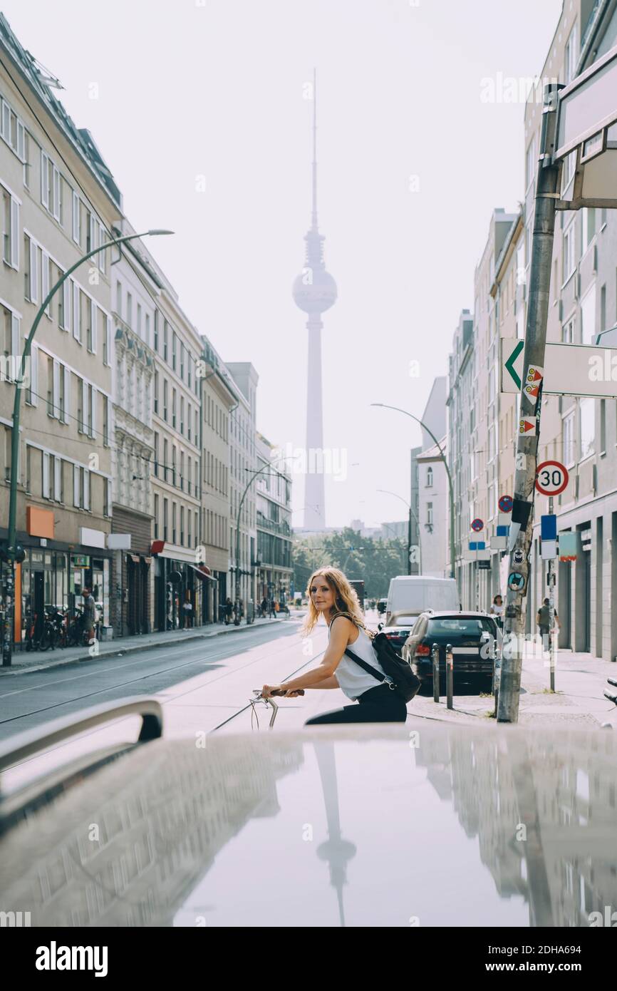 Side view of young woman riding bicycle on street in city Stock Photo ...