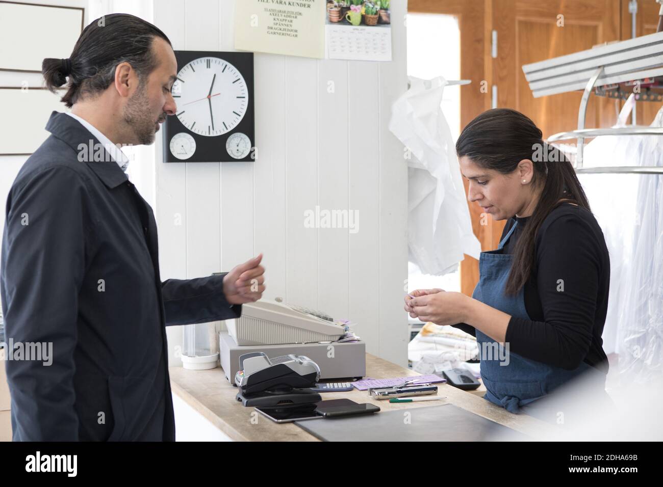 Side view of mature male customer standing at checkout with owner Stock ...