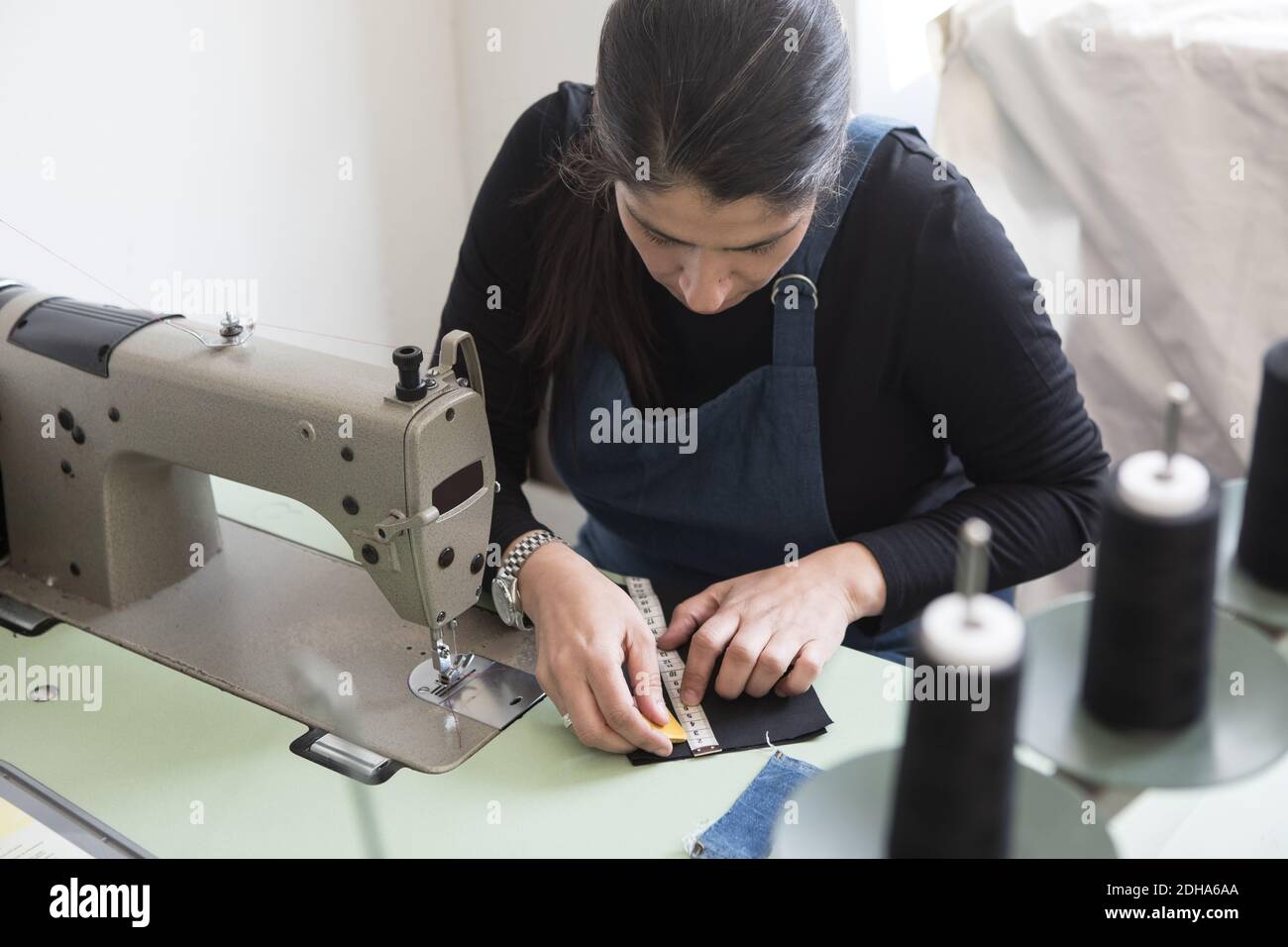 High angle view of mature female tailor measuring fabric on sewing ...
