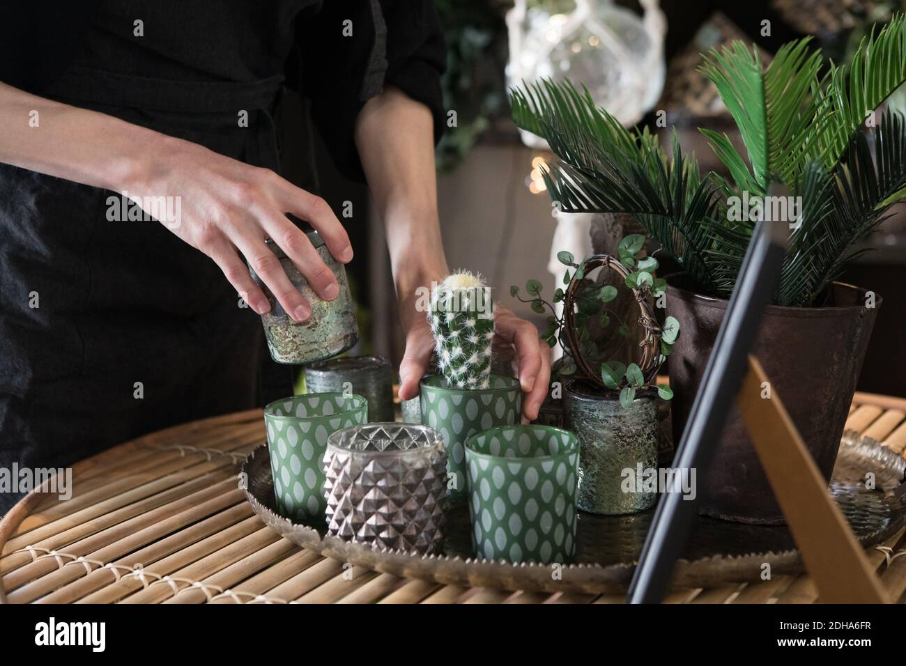 Midsection of young female owner arranging glass containers on table at ...