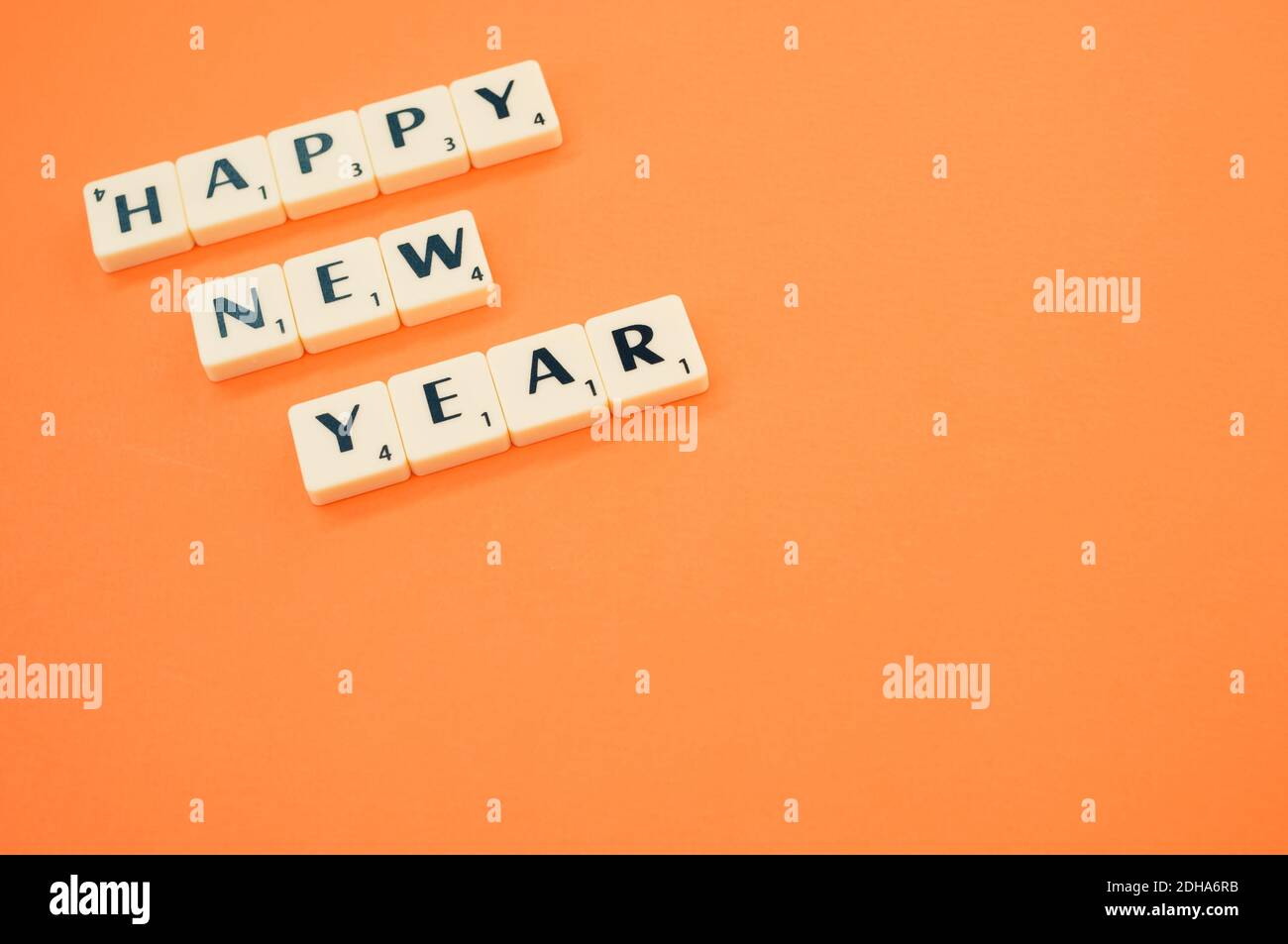 A "Happy New Year" made of white tiles on orange surface with an empty ...