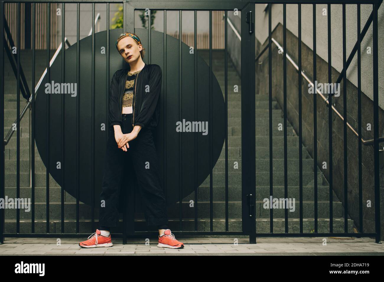 Portrait of confident young man standing against railing Stock Photo ...