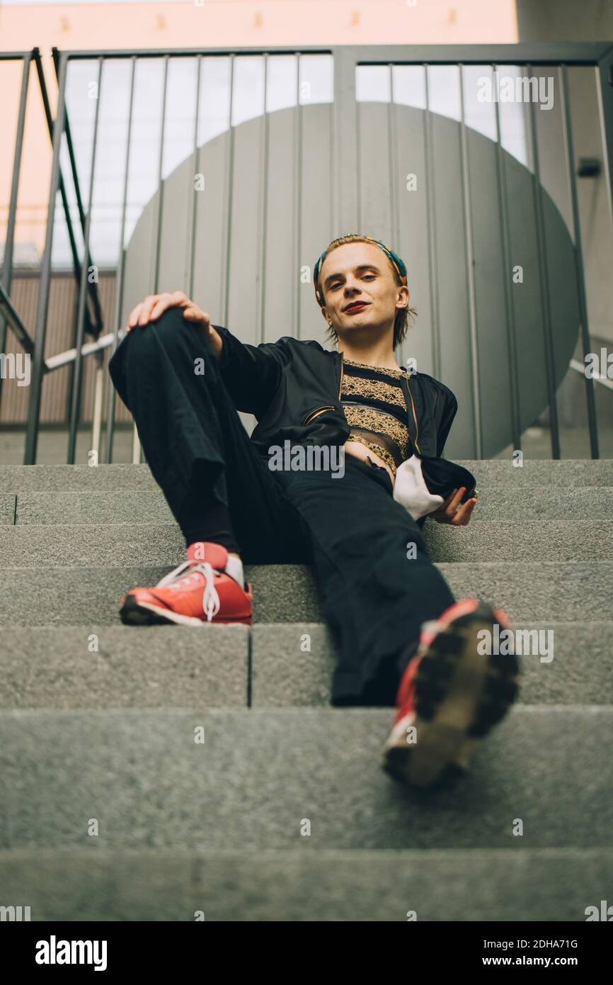 Low angle portrait of young man sitting on staircase Stock Photo - Alamy