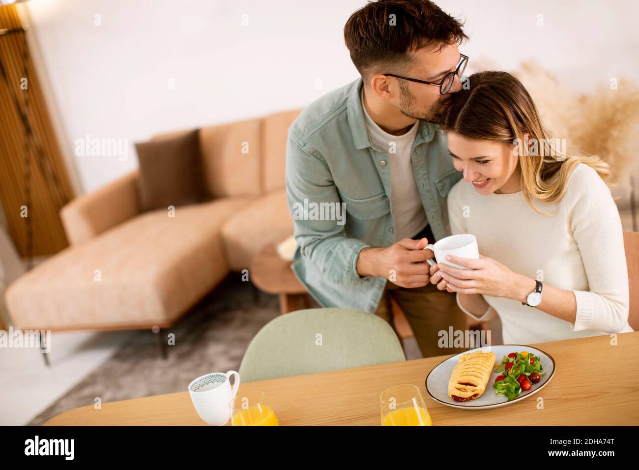 Beautiful young couple talking and smiling while eating healthy at home ...