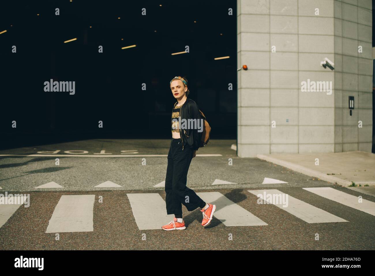 Portrait of man with hands behind back crossing road Stock Photo - Alamy
