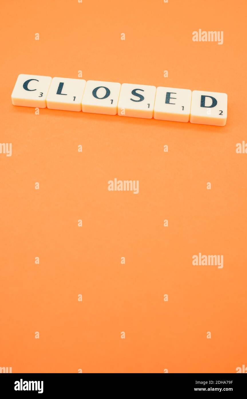 A vertical shot of the word "Closed" made of tiles on orange background ...