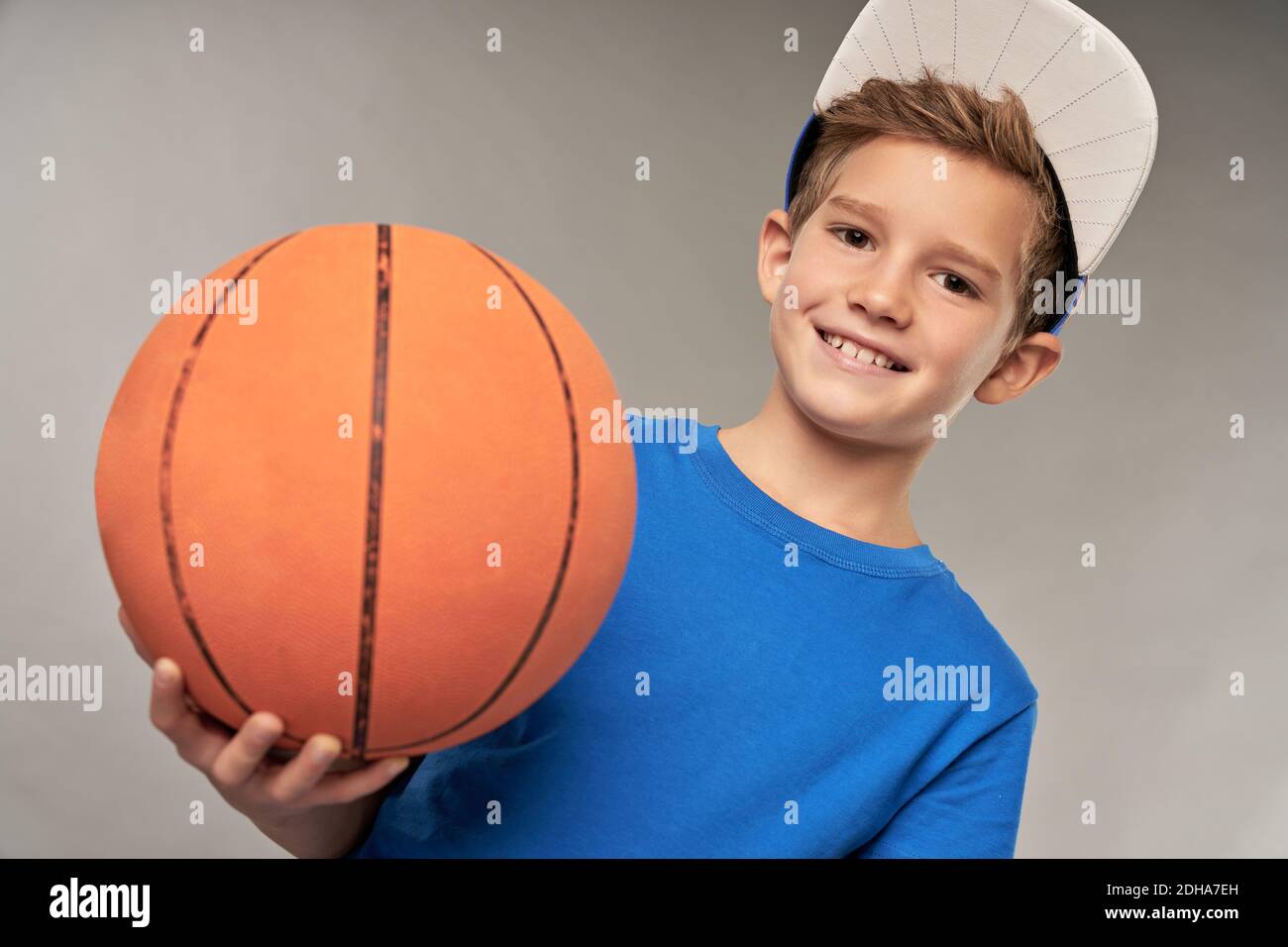 Cute boy basketball player holding game ball and smiling while standing ...