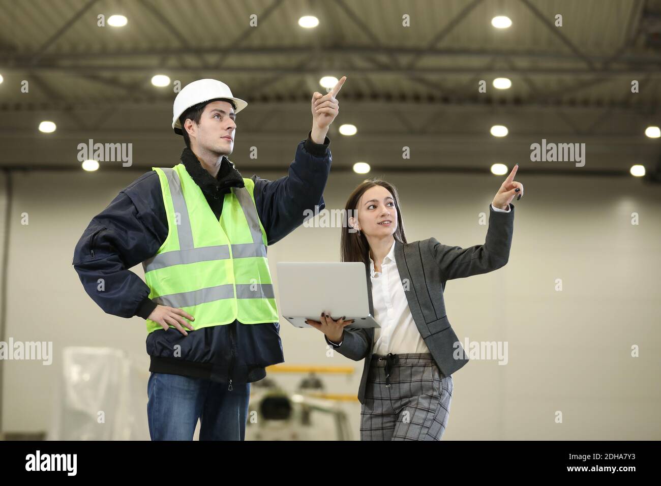 Female project manager in a business suit and white hard hat holds ...