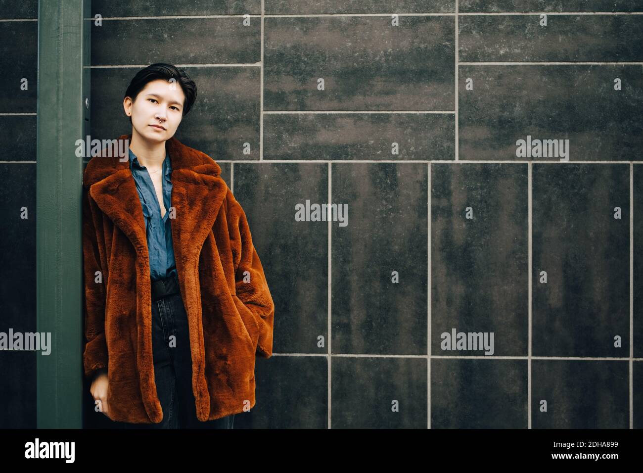 Portrait of contemplating young woman standing against wall Stock Photo ...