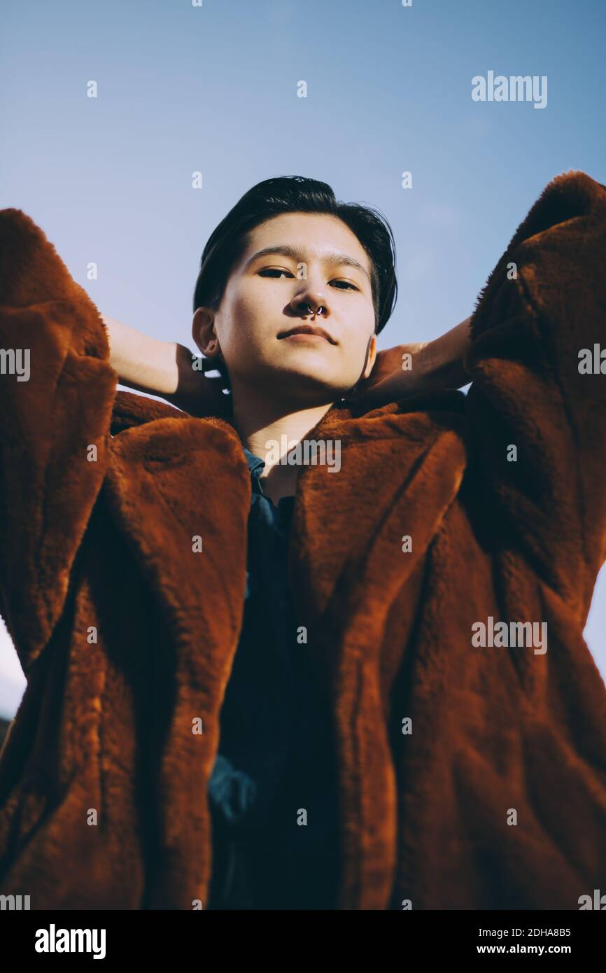Low angle portrait of woman with hands behind head against sky Stock ...
