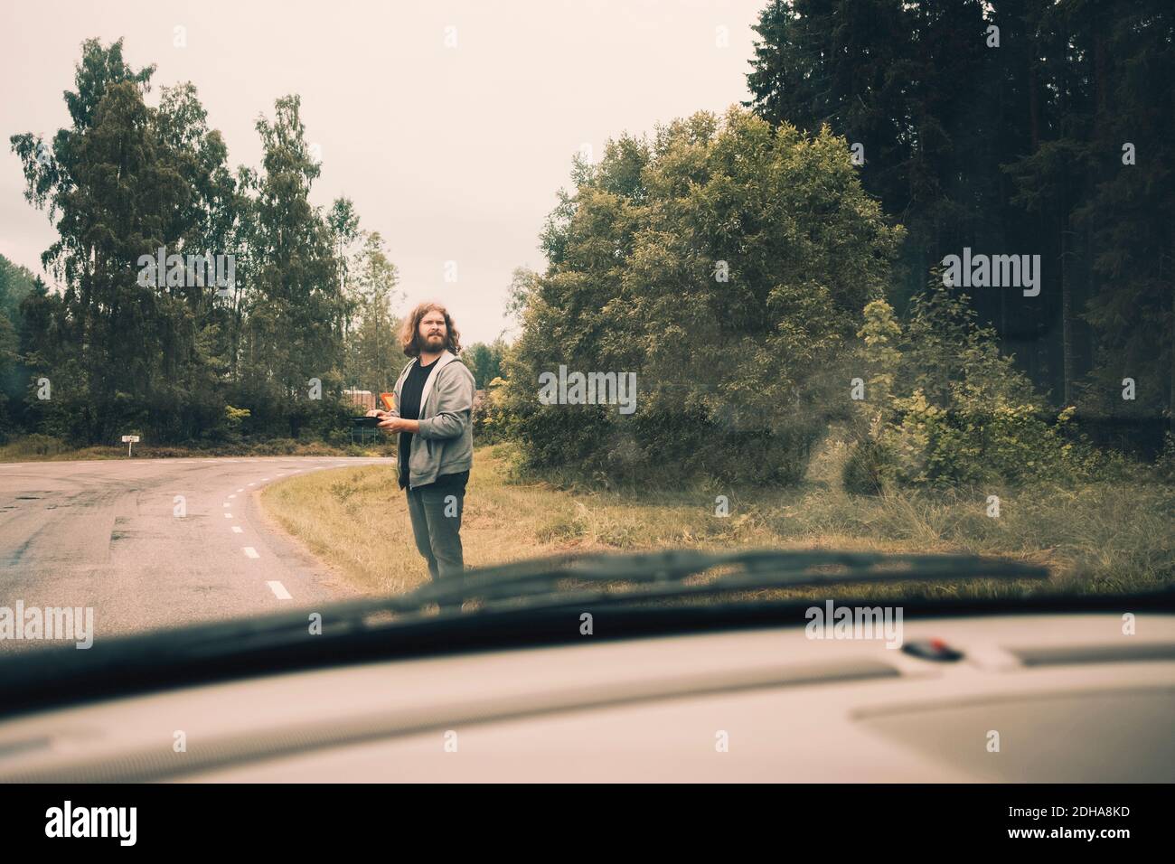 Man standing on roadside seen through car windshield Stock Photo - Alamy