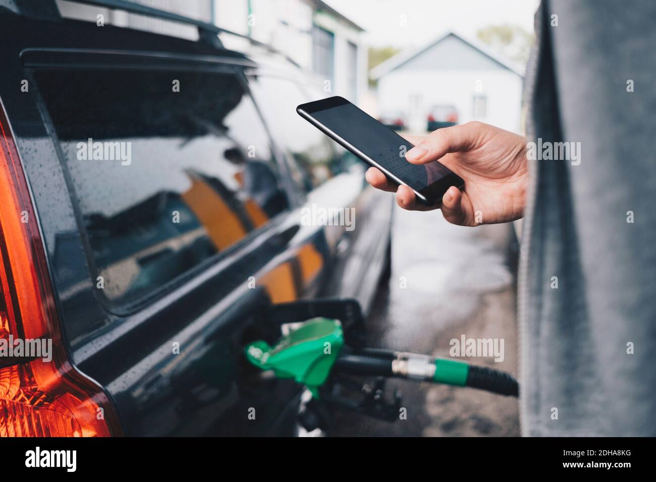 Man using mobile phone while refueling car at gas station Stock Photo ...