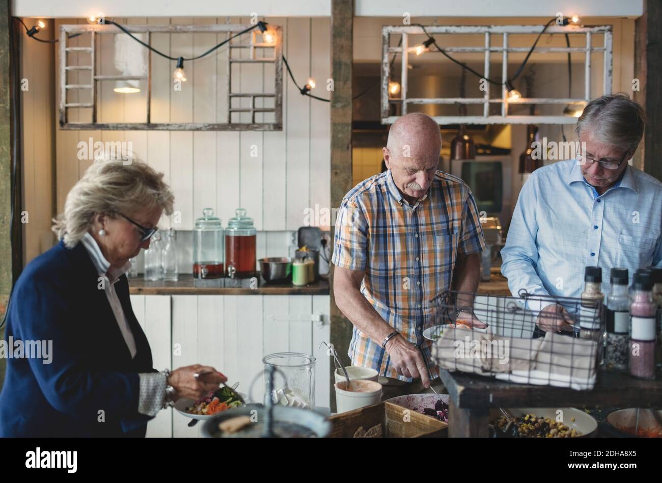 Senior male and female friends at buffet counter in restaurant Stock ...