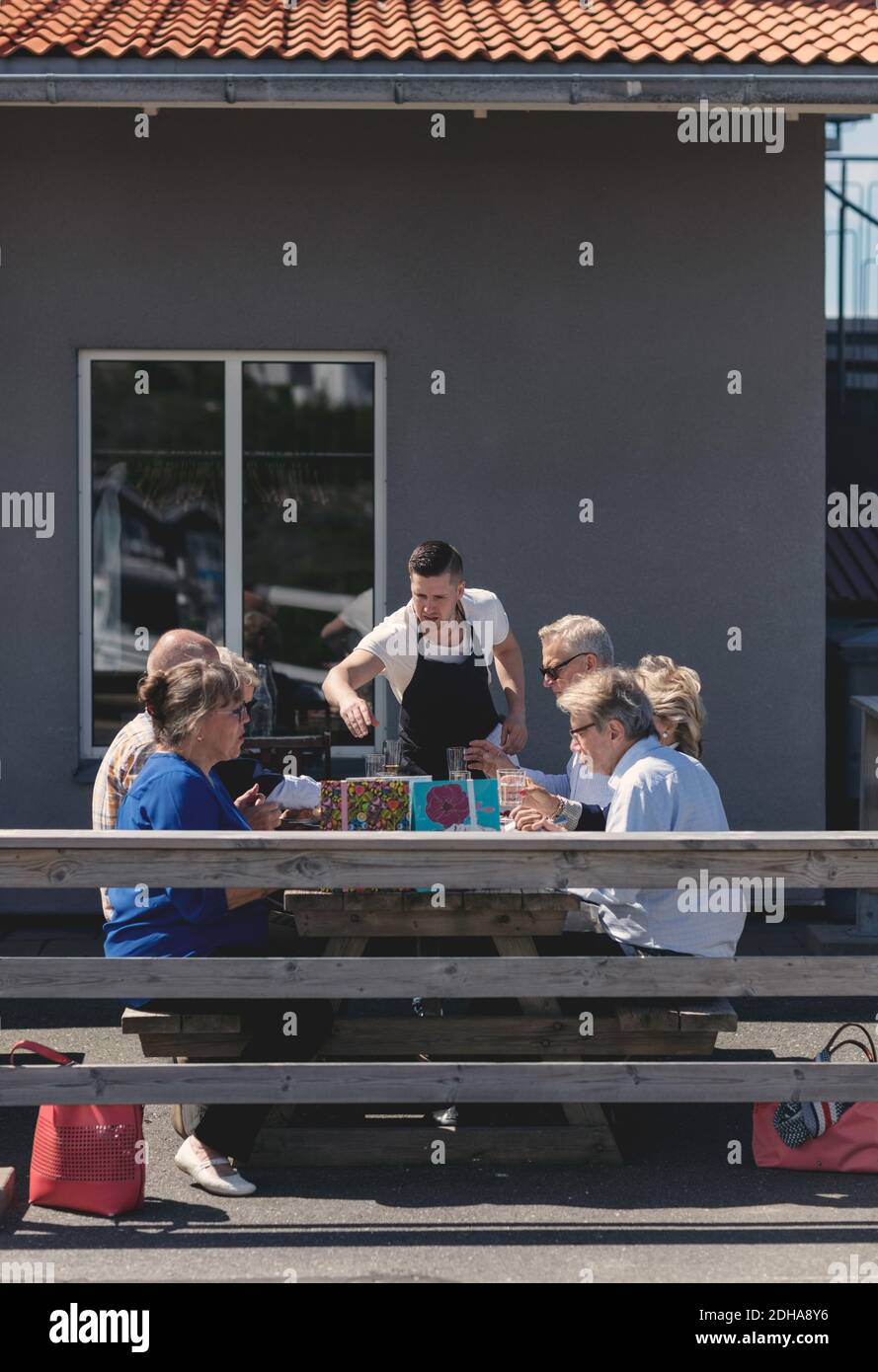Young waiter serving food to senior friends outside restaurant Stock ...