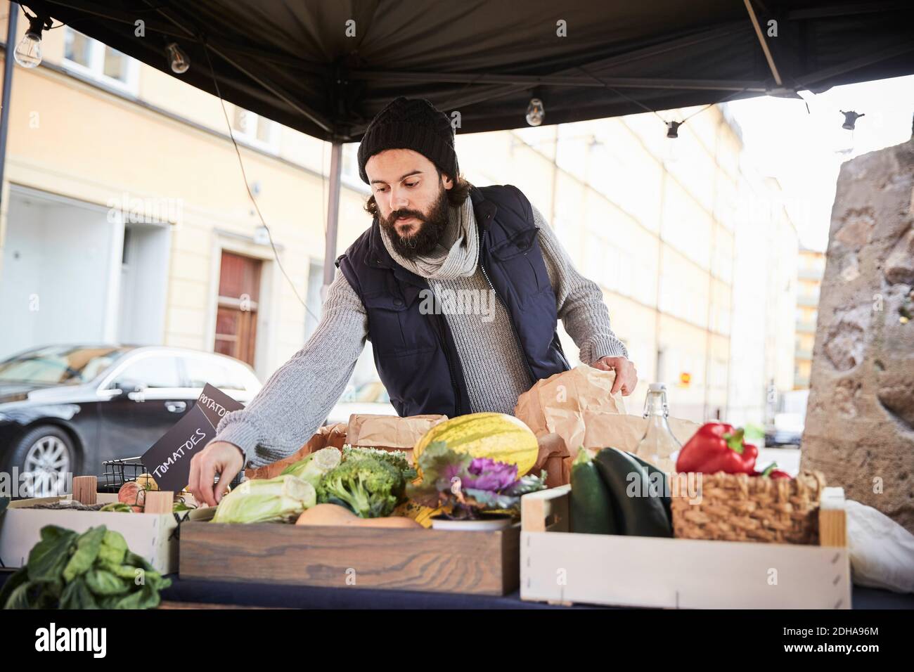 Male vendor arranging vegetables while standing at market stall Stock ...