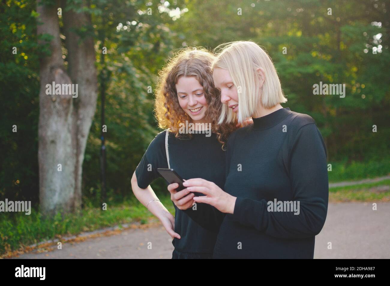 Female students using mobile phone outside university Stock Photo - Alamy