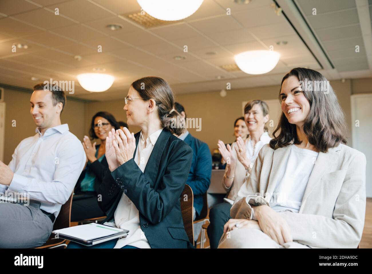Smiling male and female clapping while sitting in office workshop Stock ...