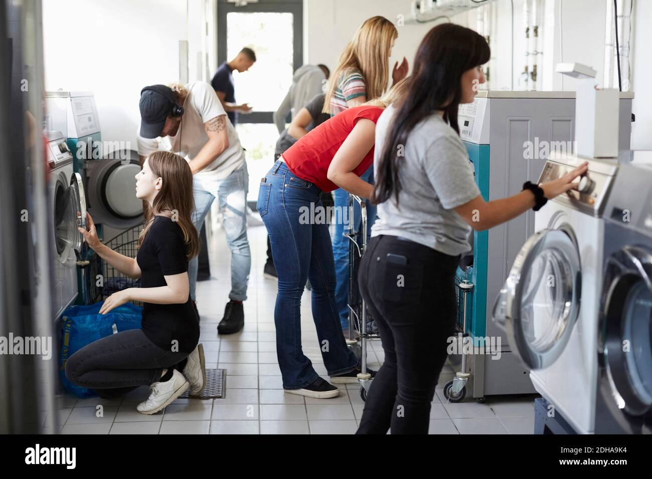 Multi-ethnic university students doing laundry at laundromat Stock ...