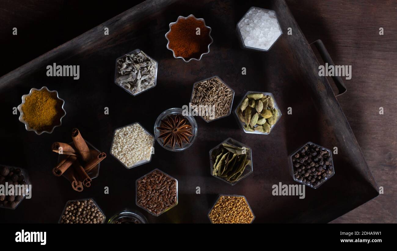 Various spices in hexagonal jars appear on a metal rusty baking sheet ...