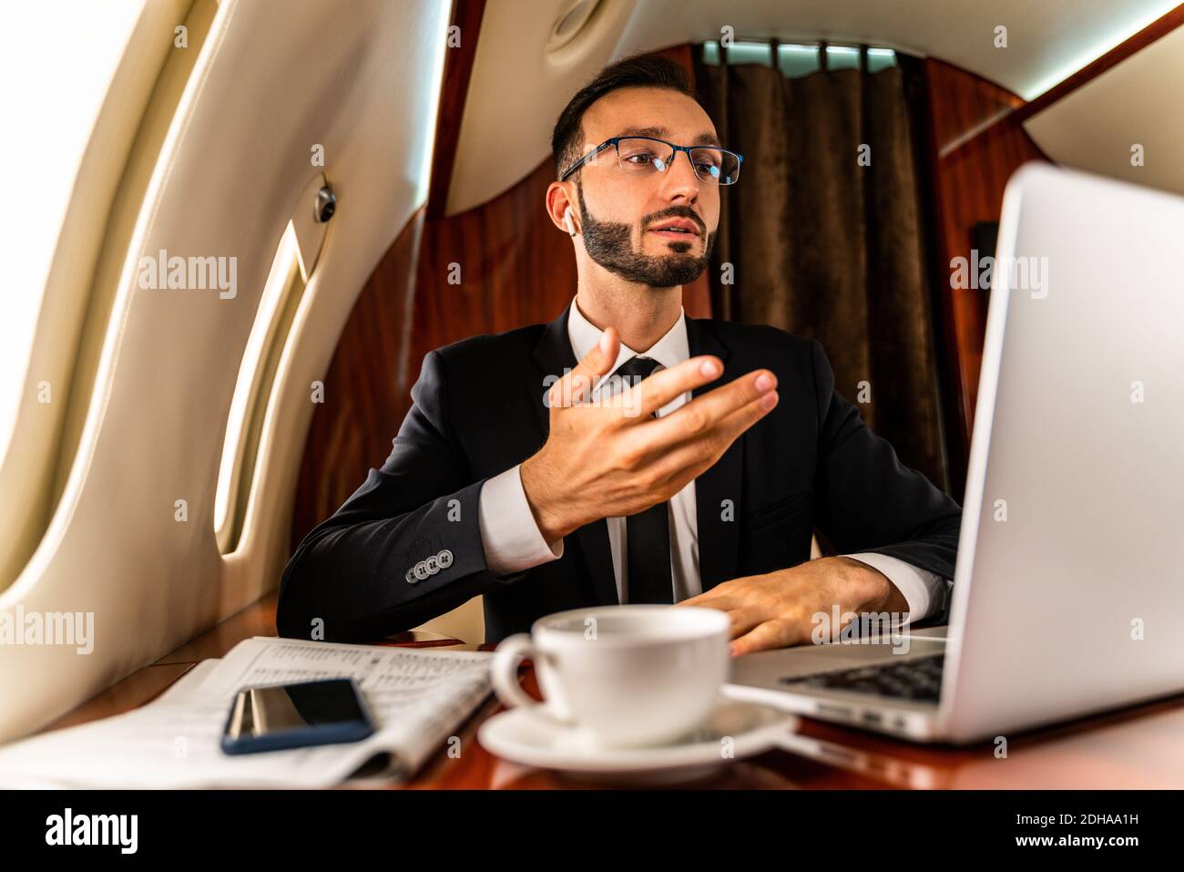 Handsome businessman wearing elegant suit flying on exclusive private ...