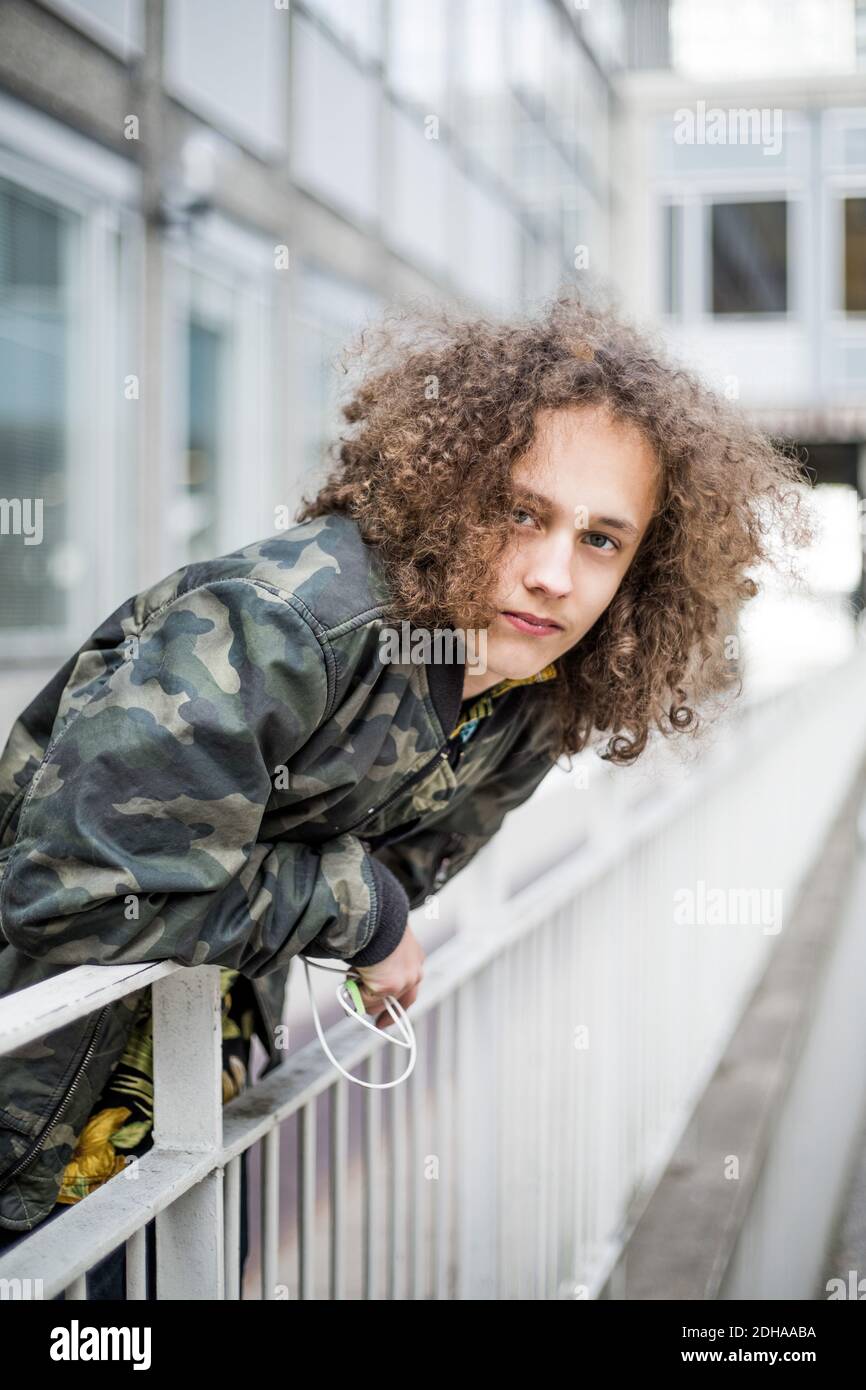 Portrait of confident teenage boy leaning on railing in city Stock ...