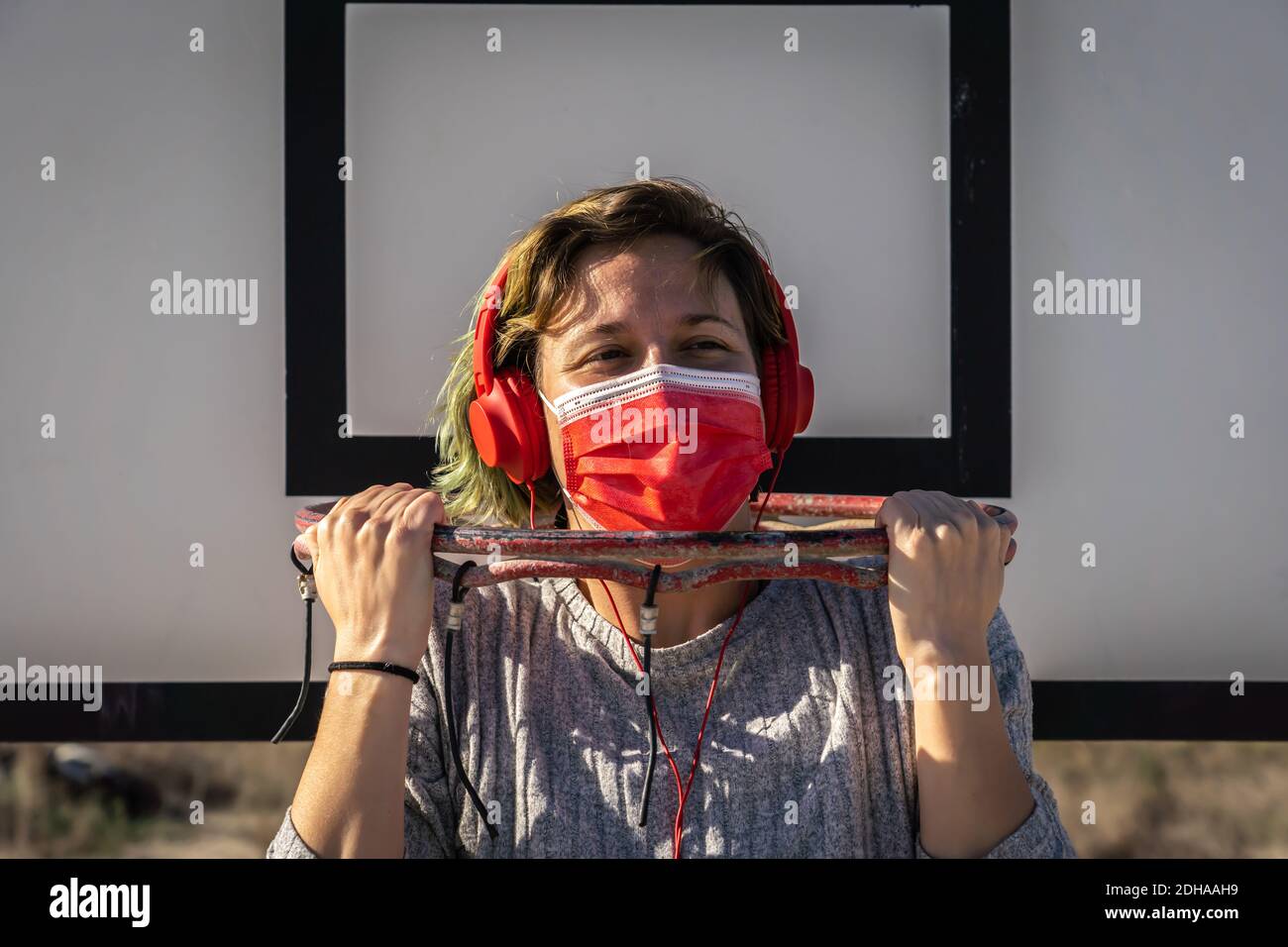 A female wearing a face mask, grabbing and hanging from a basketball ...