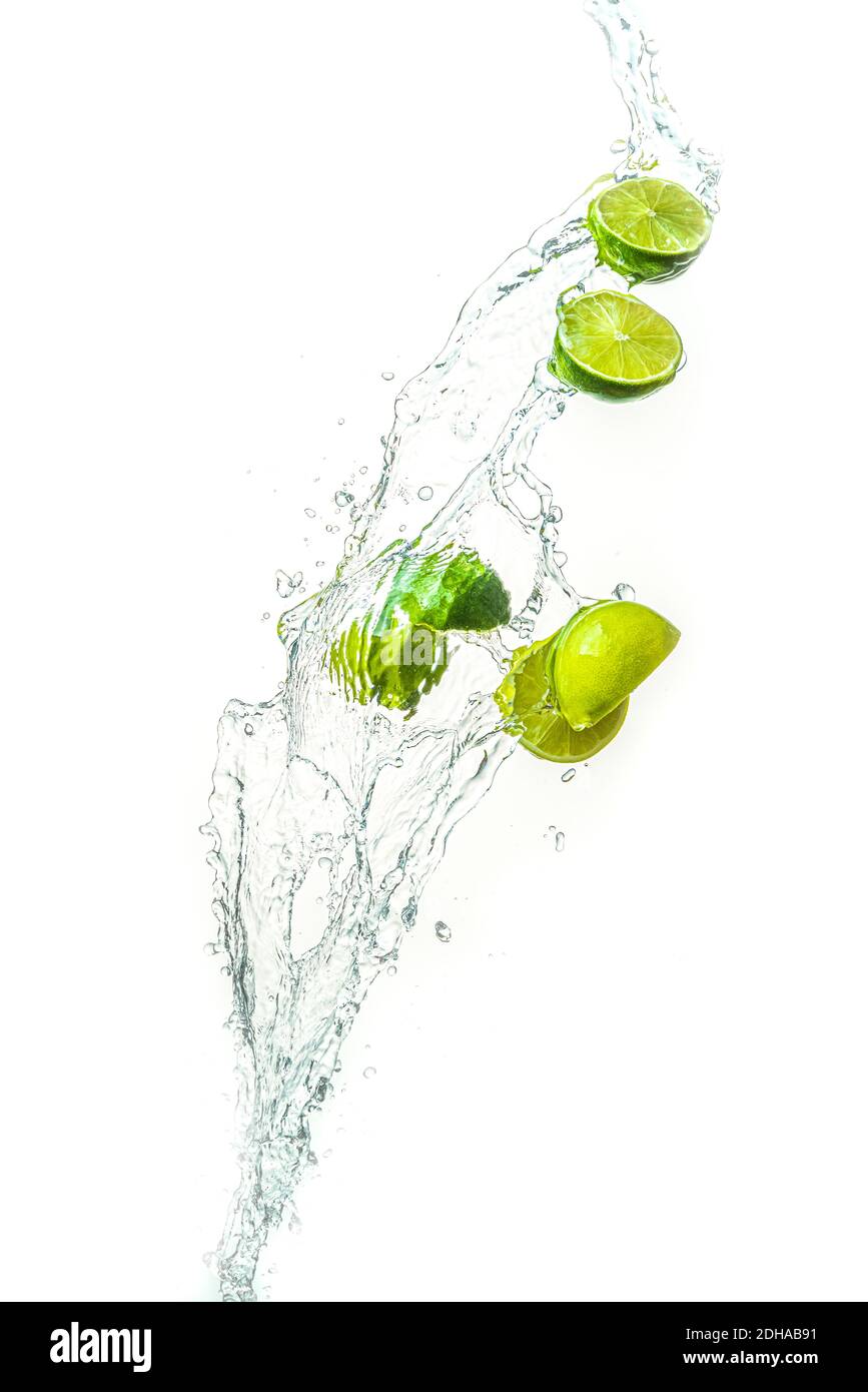 Fresh limes with water splash in midair, isolated on white background ...