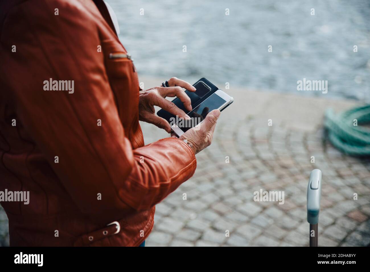 Midsection of senior woman using mobile phone on sidewalk Stock Photo ...