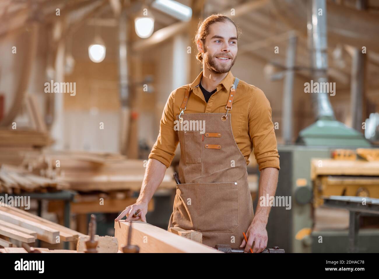 Portrait of a handsome carpenter, standing near the workbench at the ...