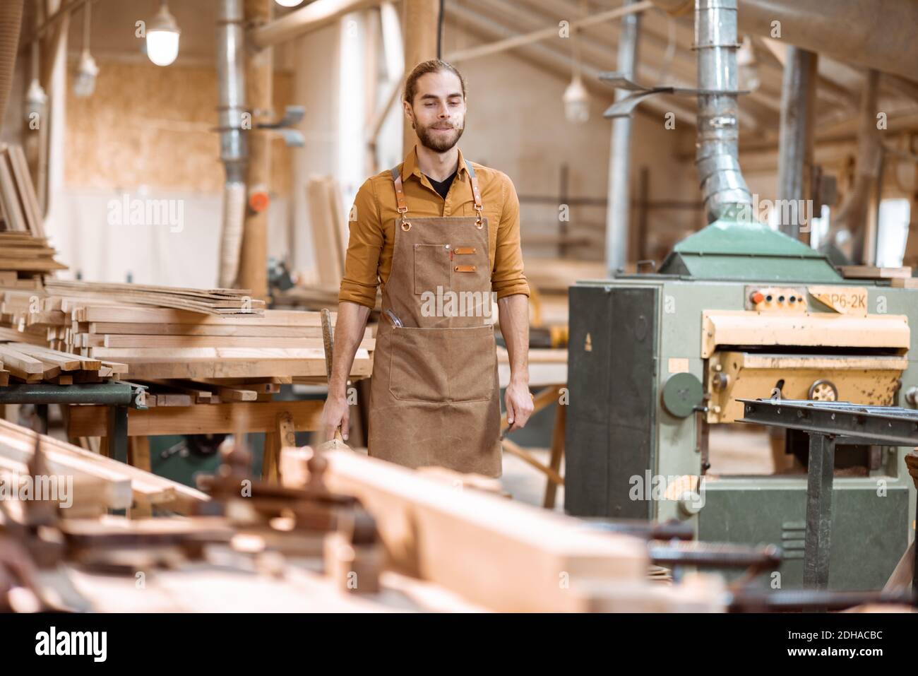 Portrait of a handsome carpenter, standing near the workbench at the ...