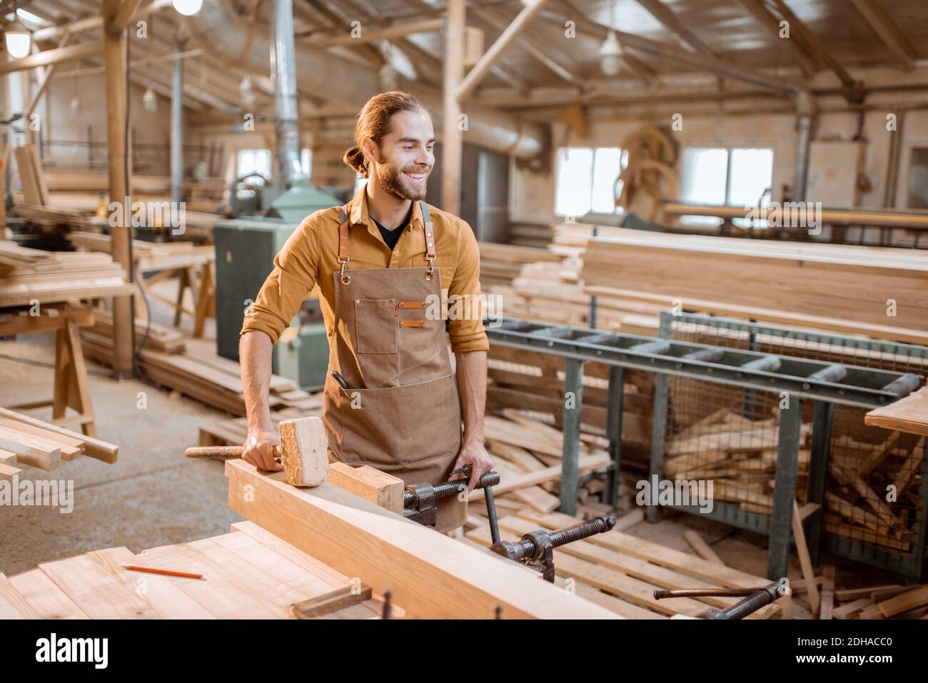 Portrait of a handsome carpenter, standing near the workbench at the ...