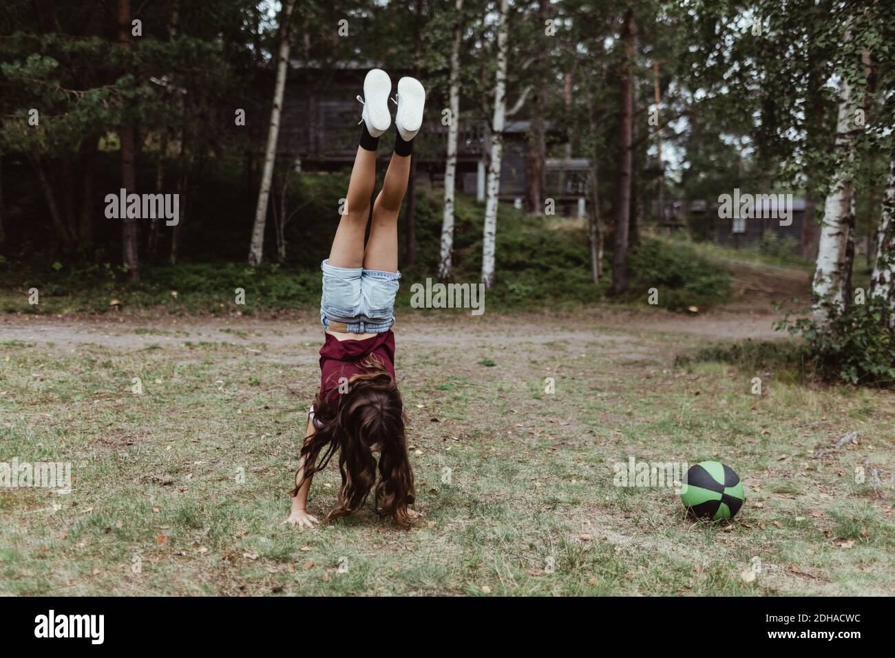 Full length of girl doing handstand in forest Stock Photo - Alamy