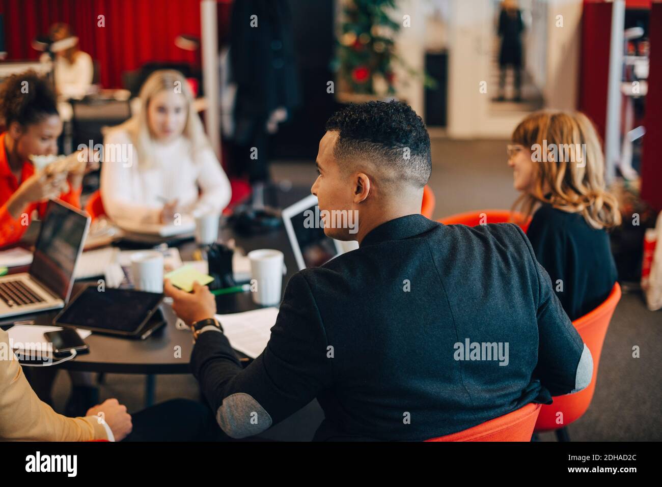 Businessman discussing with colleagues while sitting at conference ...
