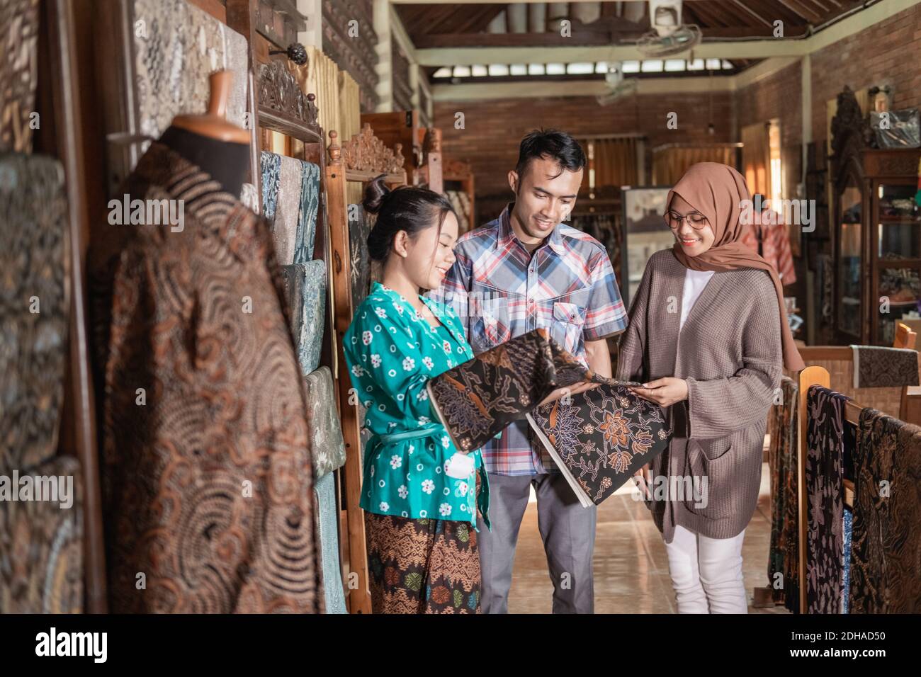 a woman showing the traditional batik cloth she sells to customer Stock ...