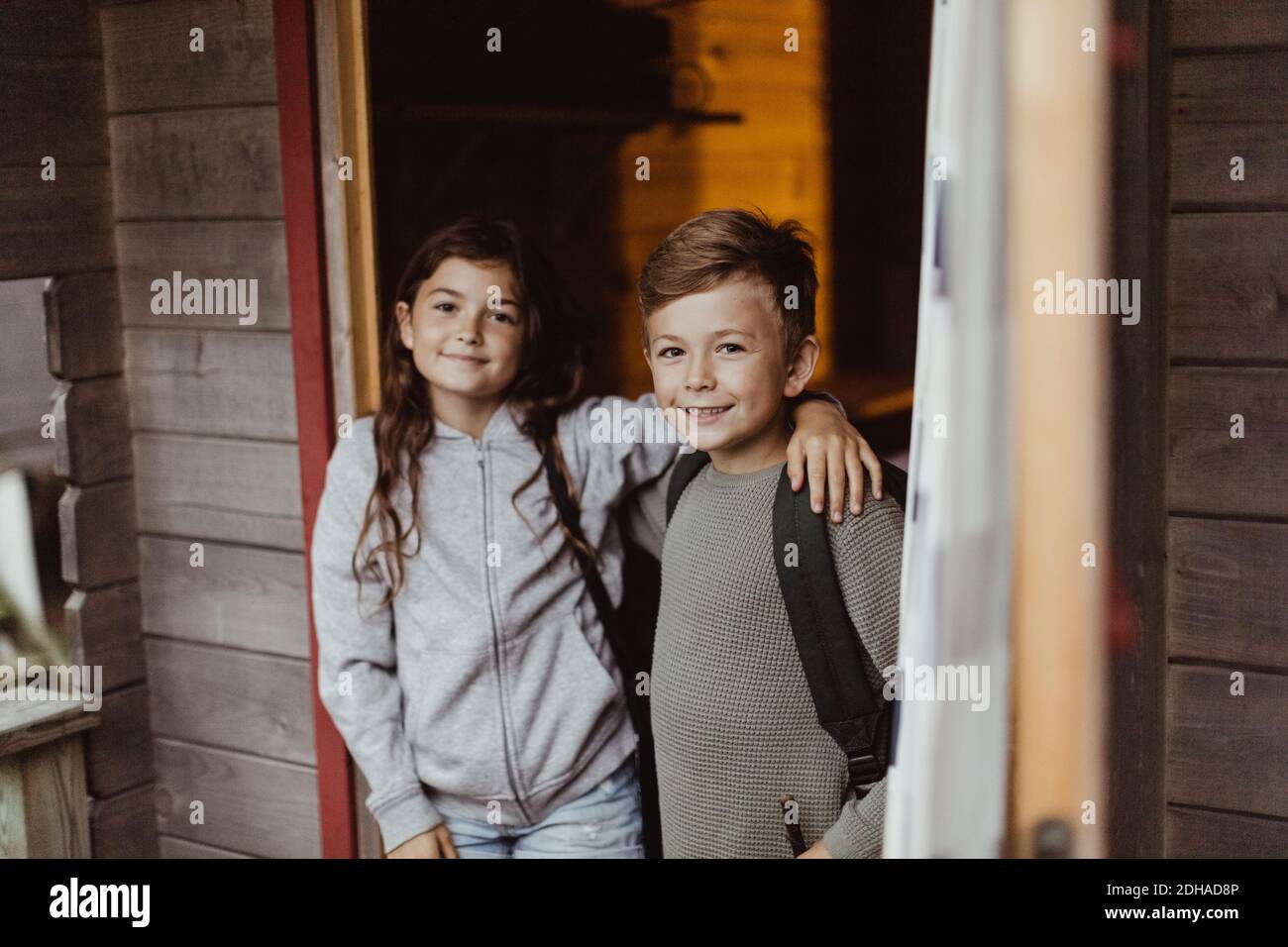 Portrait Of Smiling Brother Arm Around Standing With Sister Against