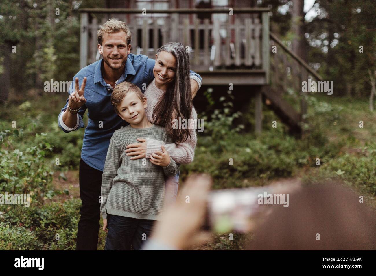 Portrait of smiling family taking pictures while standing in backyard ...