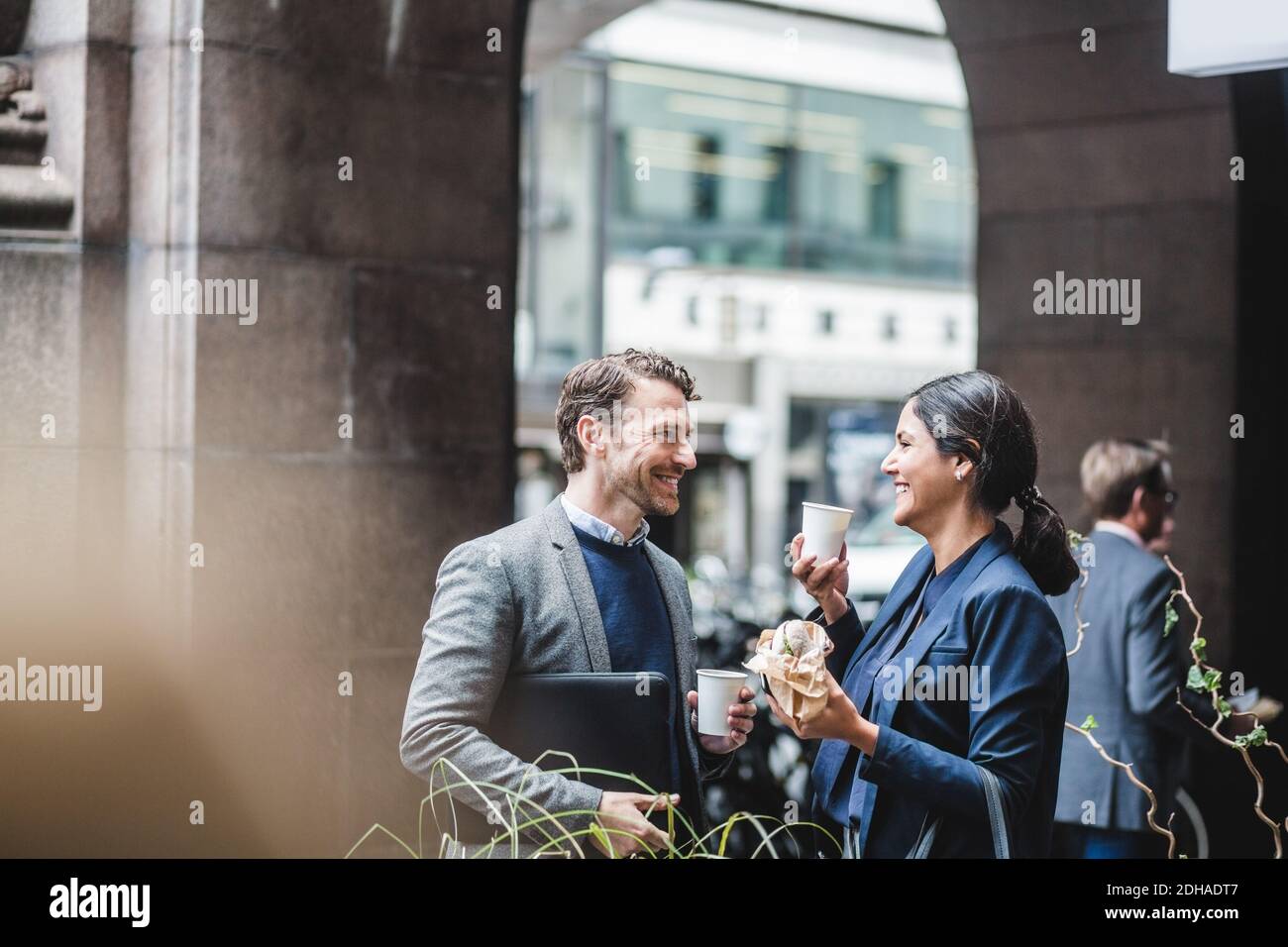 Happy business people with coffee standing at sidewalk cafe Stock Photo ...