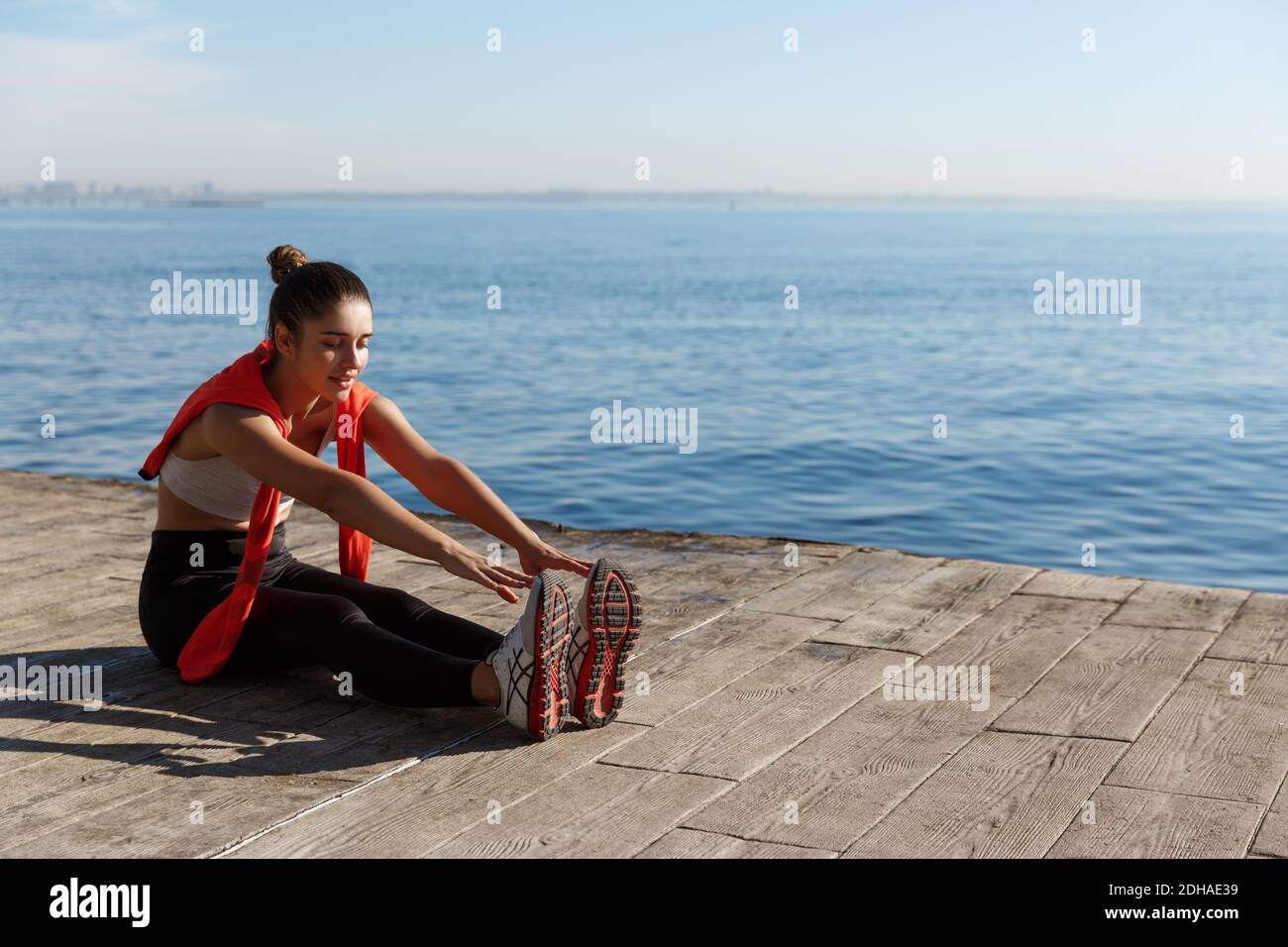 Outdoor shot of beautiful fitness woman stretching and training near ...