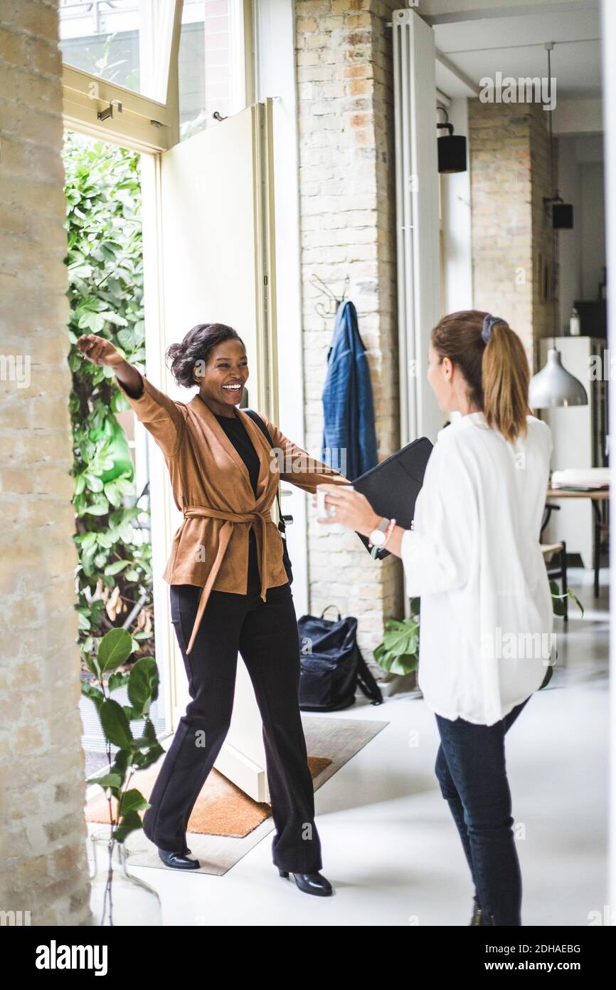 Happy female architect greeting coworker while entering in house Stock ...