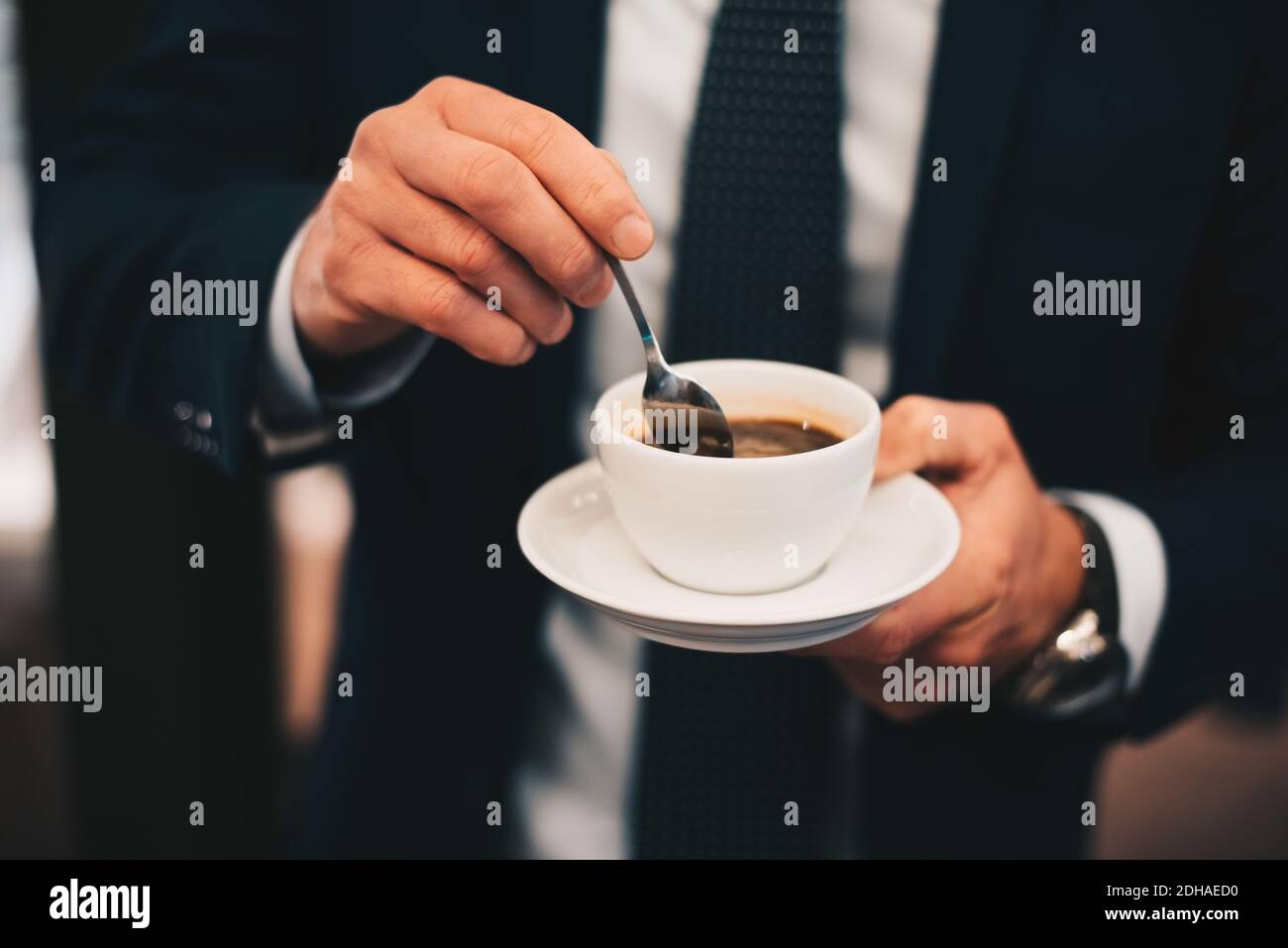 Midsection of businessman stirring coffee from spoon in cafe Stock ...