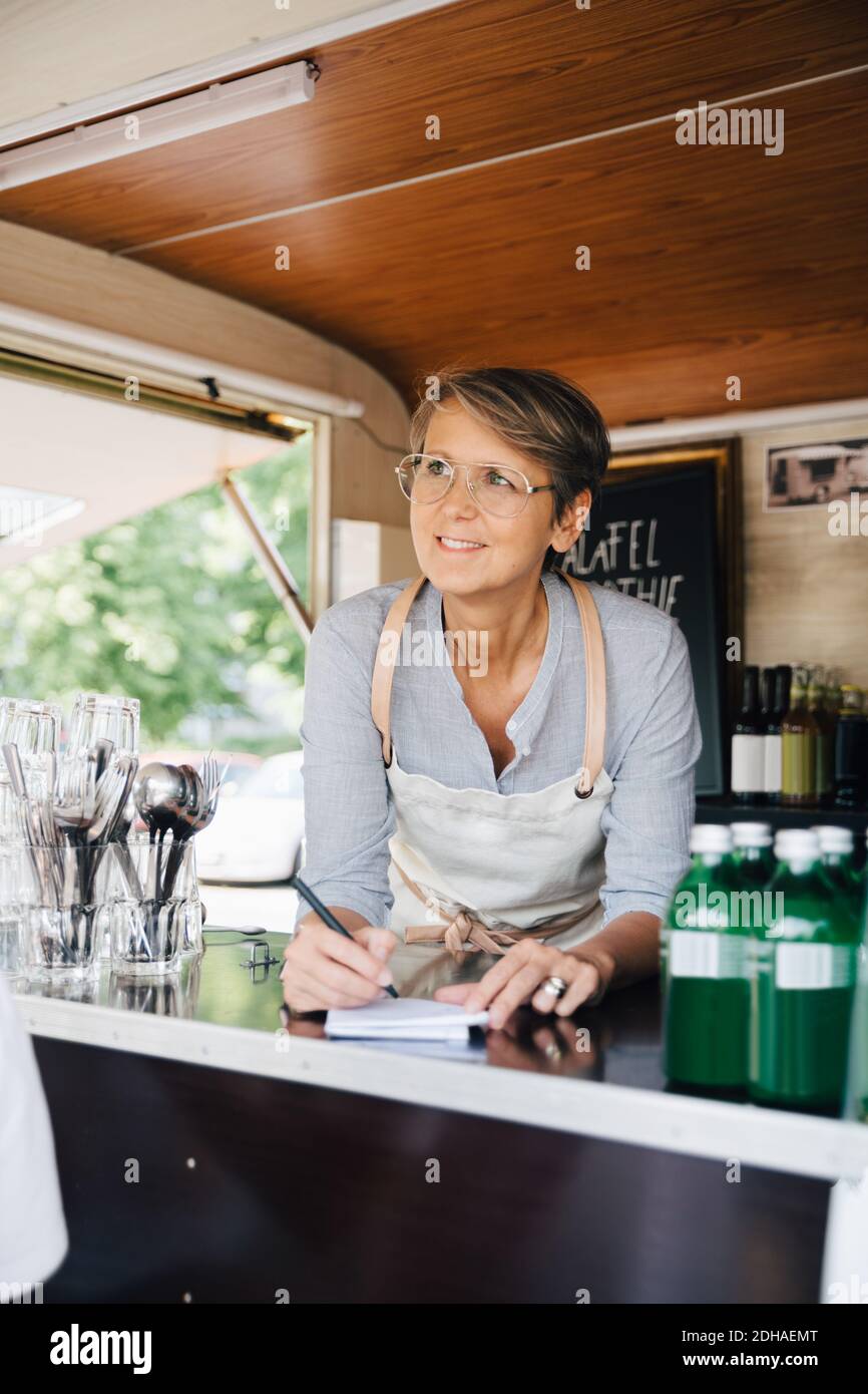 Mature owner taking order while standing in commercial land vehicle ...