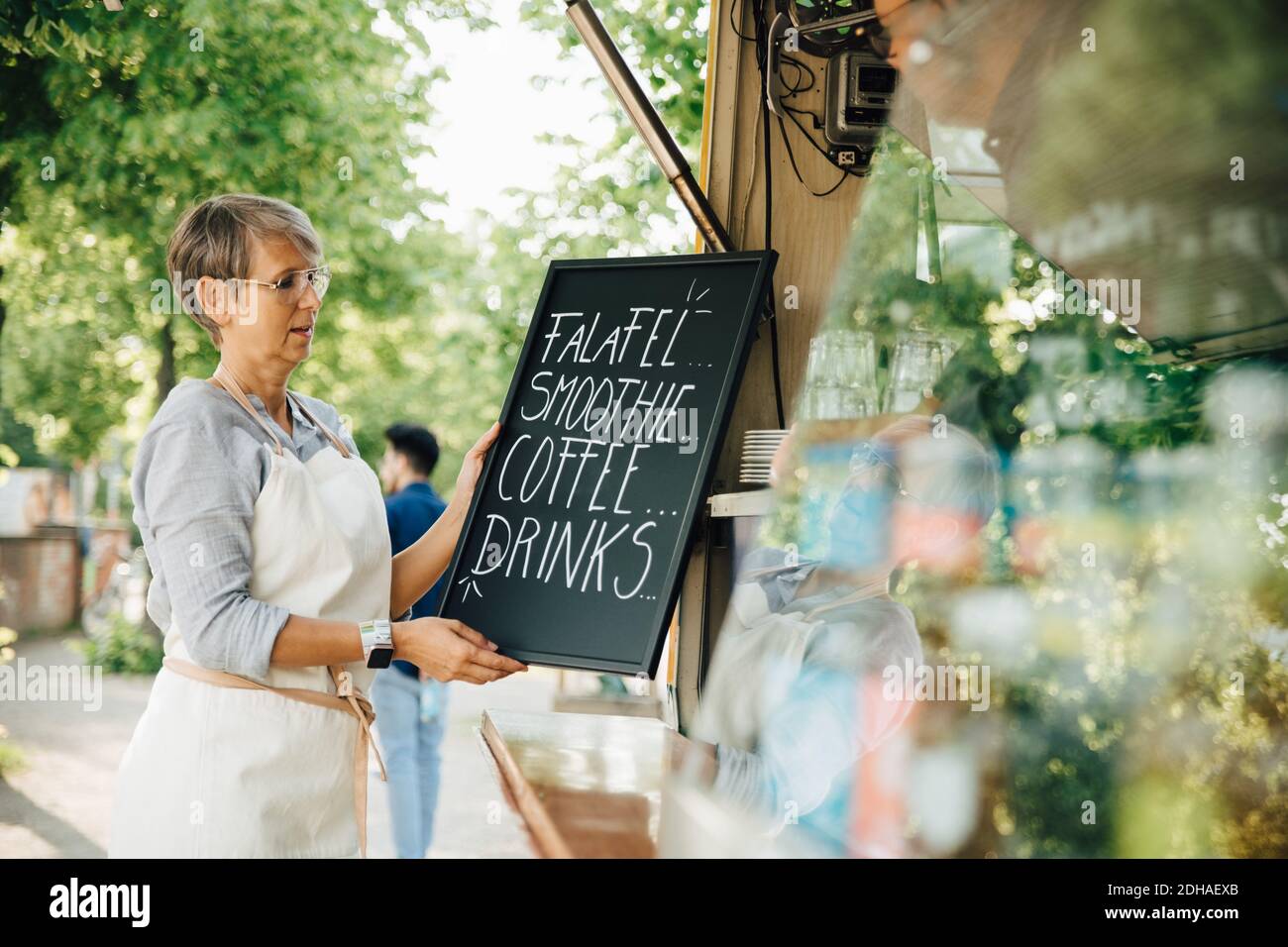 Female owner positioning board on concession stand while standing by ...