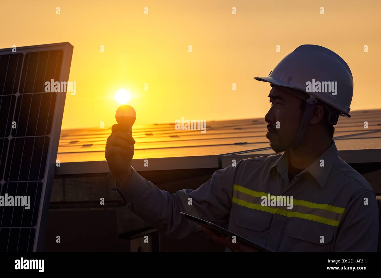 Solar energy panels and Light bulb in hand, Green energy concept sunset ...