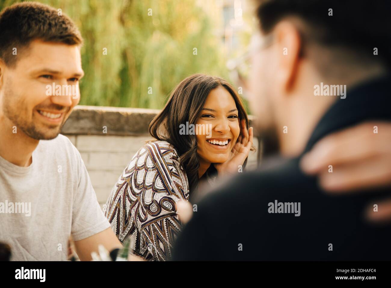 Young female smiling while sitting with friends at social gathering ...
