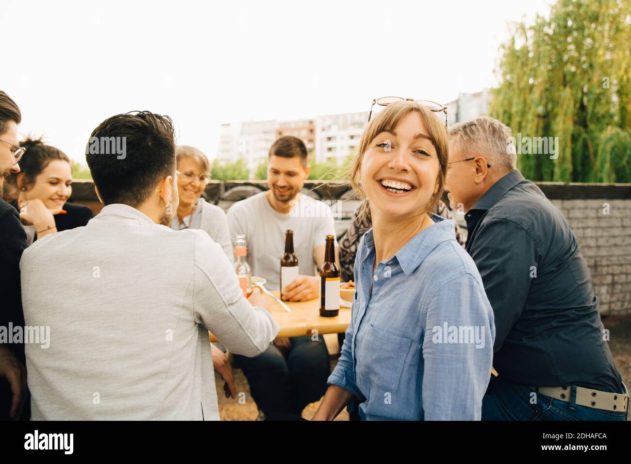 Portrait of smiling female sitting with friends and enjoying at social ...