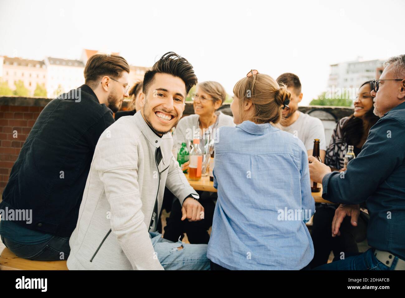 Portrait of happy man sitting with friends and enjoying at social ...