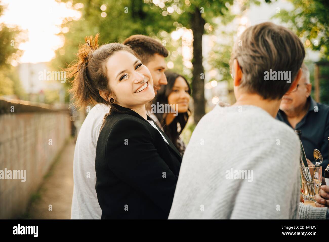 Portrait of smiling young female sitting with friends and enjoying at ...