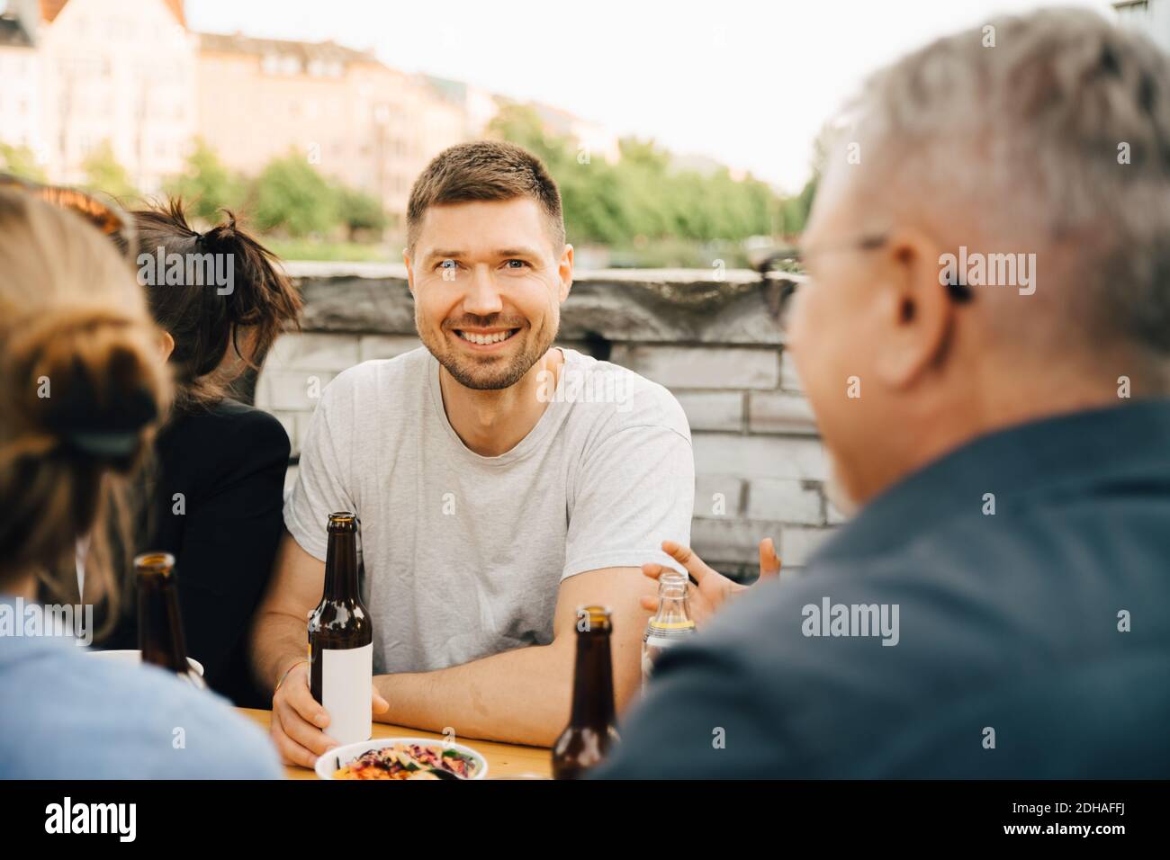 Portrait of happy man sitting with friends and enjoying at social ...